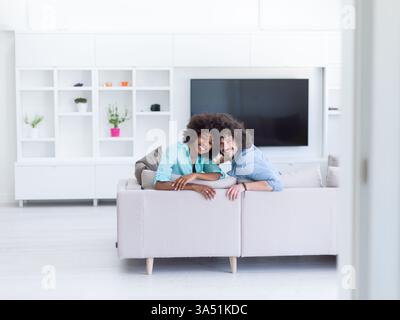 Young multiethnic couple relaxing at luxury home with tablet computers reading in the living ...