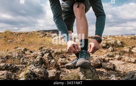 Chinese male trail runner tying his shoelaces before running Stock ...