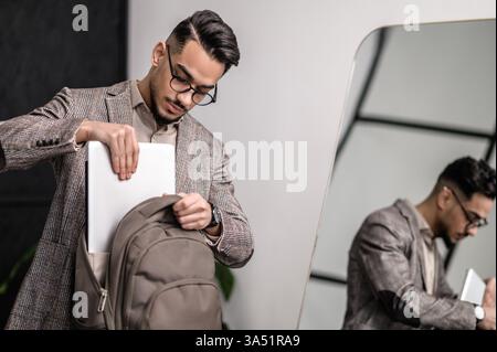 Packing a backpack. A stylish man apacking his backpack before leaving ...