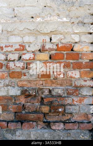 An aged red brick wall showcases visible cracks and worn mortar. The ...
