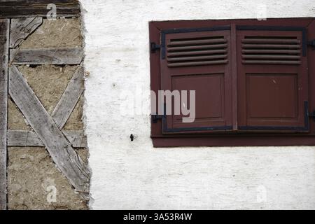 A striking wooden window hatch in a barn wall with a peeling plaster ...