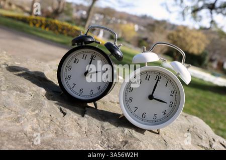 Ein Wecker zeigt zwei Uhr und der andere drei Uhr. Die Uhren werden am ...