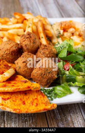 Falafel plate with salad and french fries isolated on rustic background ...