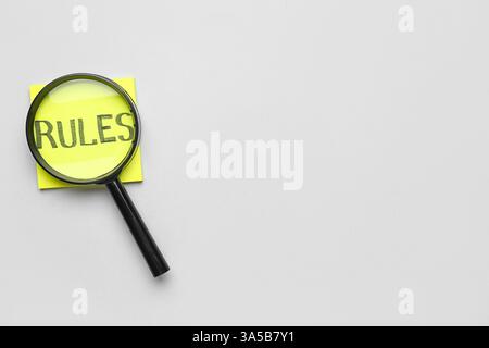 Paper with word RULES and magnifier on blue background Stock Photo - Alamy