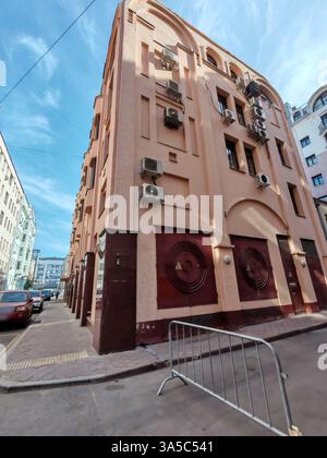 A modern peach building with air conditioning units and round red ...