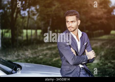 Portrait of young attractiave man in white shirt leaning on his new ...