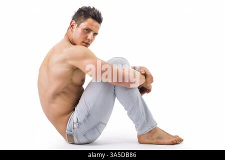 Handsome young bodybuilder laying down on the floor, showing ripped abs ...