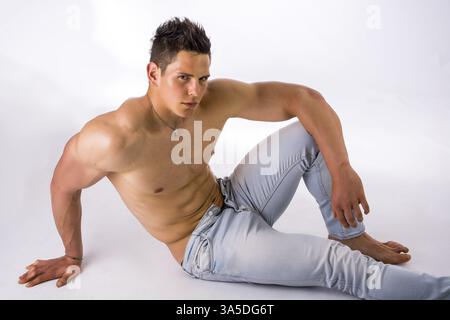 Handsome young bodybuilder laying down on the floor, showing ripped abs ...