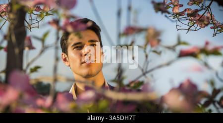 Good looking male model at couuntryside, among flowers, enjoying nature ...
