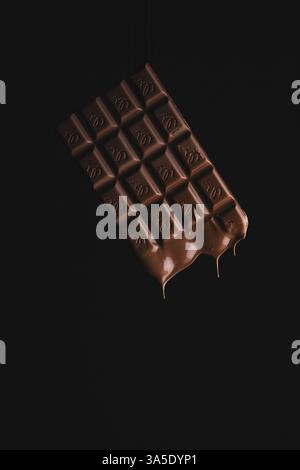 A floating chocolate bar with melting drops on a black background Stock ...