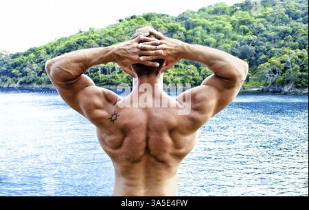 Muscular bodybuilder with hands behind his head showing back, shoulders ...