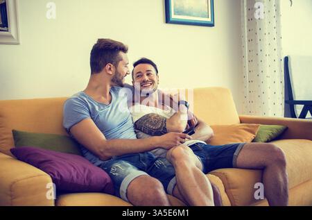 two guys sitting on the couch, talking on the smartphone and ...