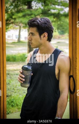 Sporty man drinking protein shake on dark background Stock Photo - Alamy