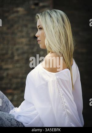 side view of girl in shirt and shorts holding laptop isolated on blue ...
