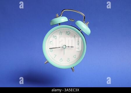 Turquoise alarm clock in air on yellow background Stock Photo - Alamy