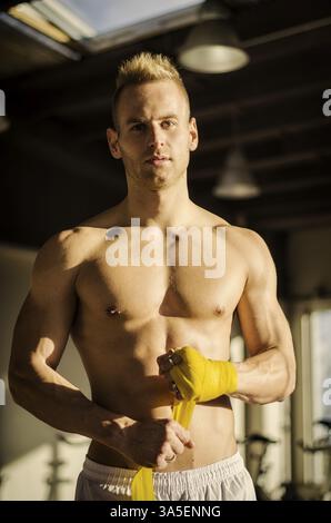 Muscular young man wrapping bandage around his hands for boxing Stock ...