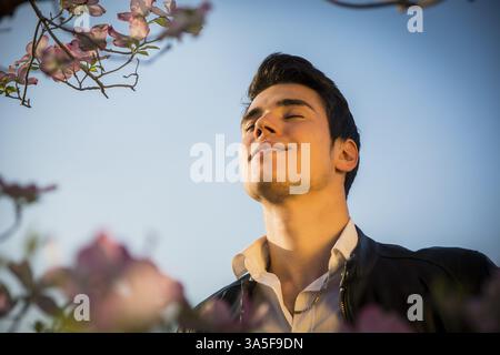 Good looking male model at couuntryside, among flowers, enjoying nature ...