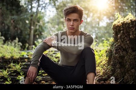 One handsome blue eyed young man in urban setting in European city park ...