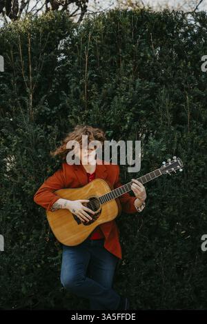 Red-haired guitarist with guitar in the green bush Stock Photo - Alamy
