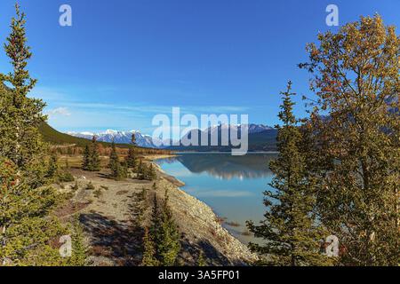 Snow-covered rocky mountaintops surround pristine alpine lakes on a ...