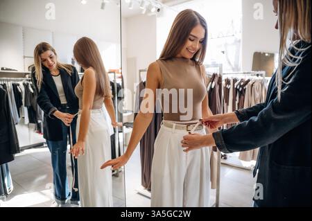 Measuring the waist. Two female friends are in the retail store ...