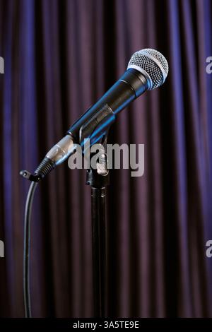 Microphone standing on a dark stage, illuminated by bright blue lights ...