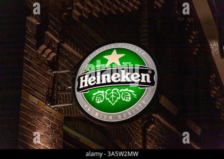 Heineken Flag sign logo at a cafe by night. Heineken is a Dutch ...