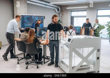 Big screen with code on the wall. People are in the office by the 3d ...