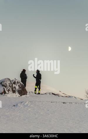 Men under moon on snowy arctic mountain viewing spot in Ersfjord Tromso ...