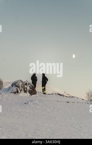 Men under moon at snowy arctic mountain viewing spot in Ersfjord ...
