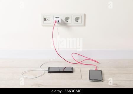 USB adapter with cables plugged into electric socket charging different ...
