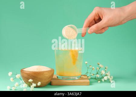 Adding collagen powder into glass with water on light blue background ...