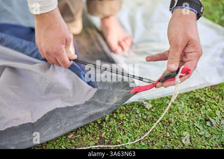 Unrecognizable man putting up the poles of his tent, in the process of ...