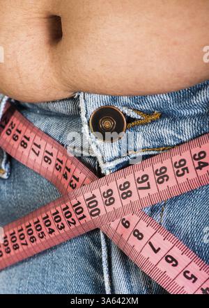 Woman showing fat belly. Pink tape measure Stock Photo - Alamy