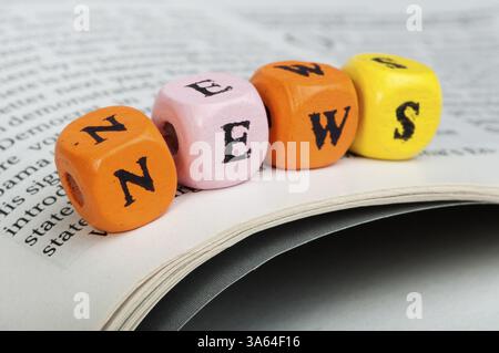 news word writing on cube front newspaper stack Stock Photo - Alamy