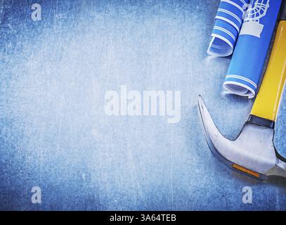 Blue rolled construction drawings claw hammer on metallic background ...