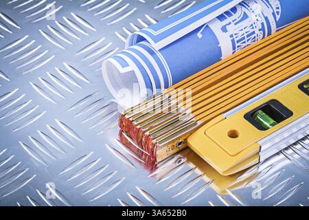 Construction level wooden meter blue blueprints on fluted metal sheet ...