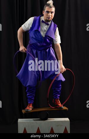 Male acrobat wearing purple costume hanging upside down performing on ...