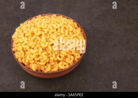Elbow macaroni on a stone black background Stock Photo - Alamy