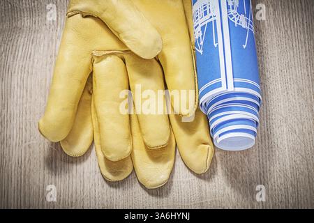 Safety gloves rolled blue engineering drawings on wooden board ...