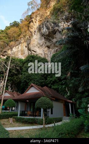 Bungalows nestled at the base of a limestone cliff in Tonsai ...