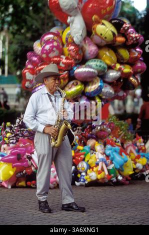 A strolling musician plays the saxophone on the street surrounding the ...