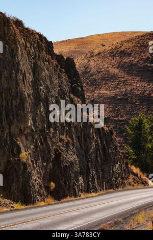 Asphalt highway through the steep red cliffs in the Zion National Park ...