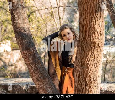 Pretty young woman in poncho with painted human skull on orange ...