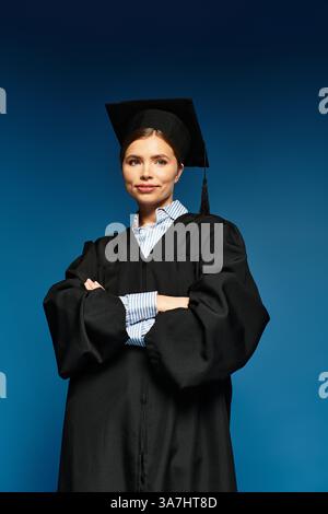 Woman in graduation gown stands smiling against an orange background ...