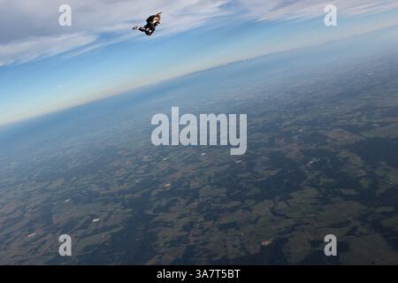 Tandem skydivers floating with parachute against blue sky over Texas ...