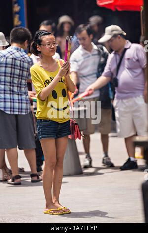 A woman prays at Chenghuang Miao or City God Temple in Yu Yuan Gardens ...