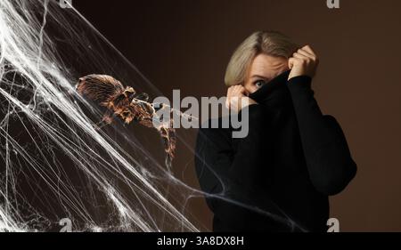 Scared woman and cobweb with spider against grey background ...