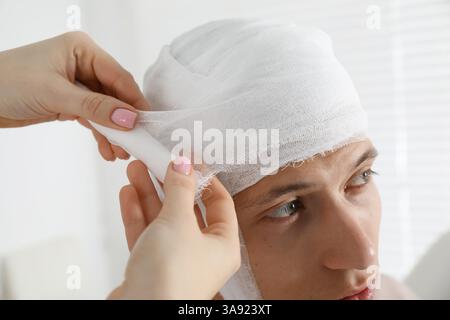 Doctor bandaging patient's head in clinic, closeup Stock Photo - Alamy
