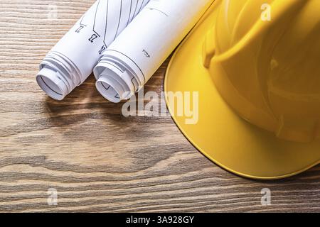 Rolled engineering drawings hard hat on wooden board construction ...